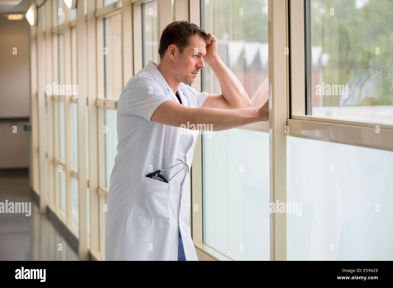 Male doctor standing in hospital looking out of window Stock Photo - Alamy