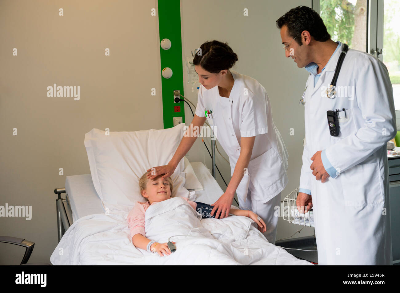Medical attendants examining to a girl patient in hospital bed Stock ...
