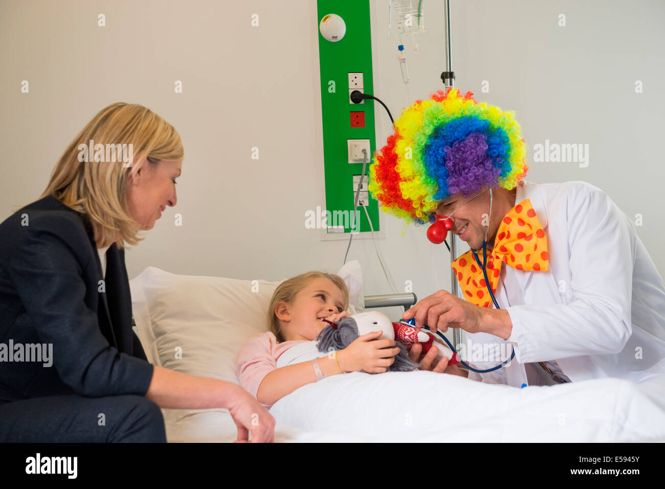 Male doctor wearing clown costume making girl patient smile in hospital ...