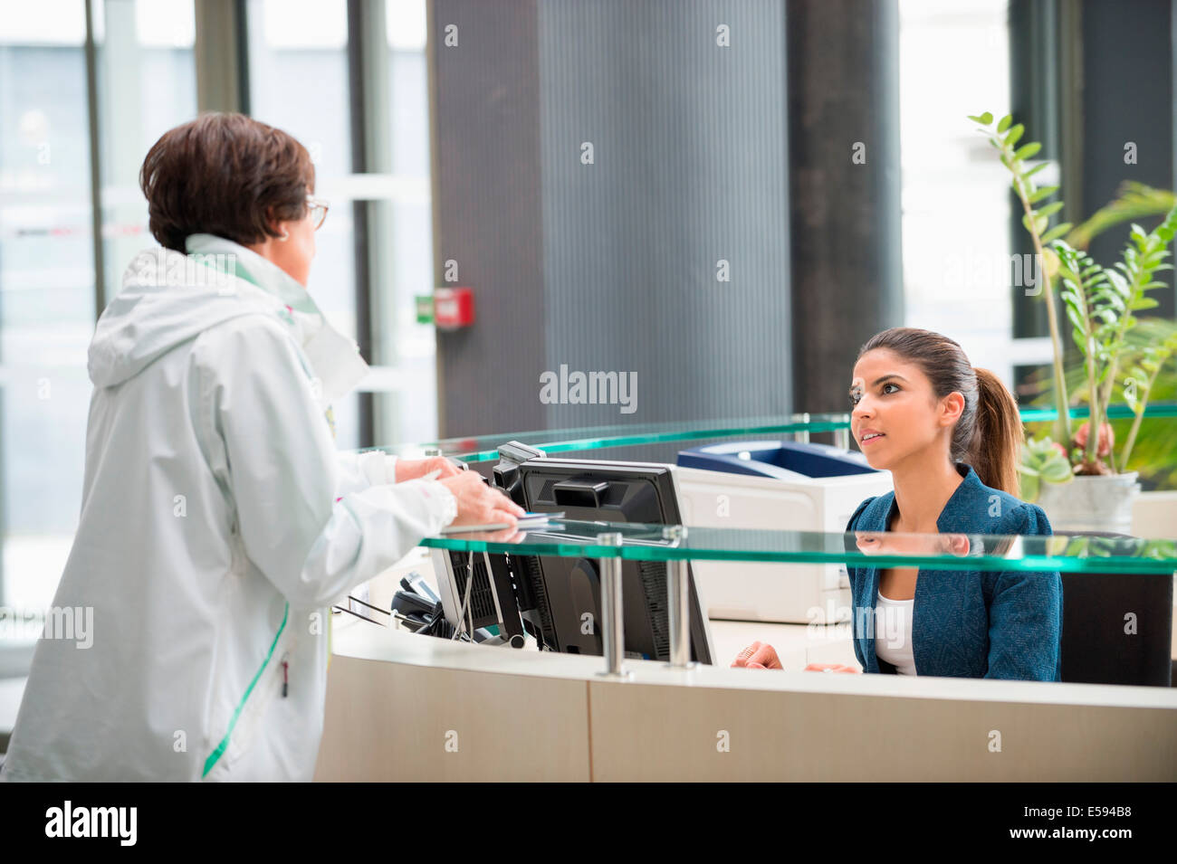Woman discussing at reception desk Stock Photo - Alamy