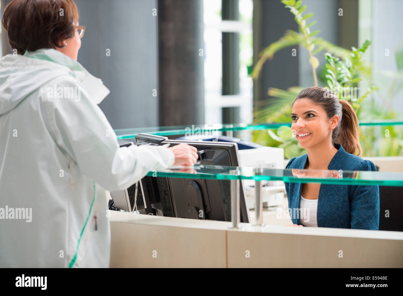 Woman discussing at reception desk Stock Photo - Alamy
