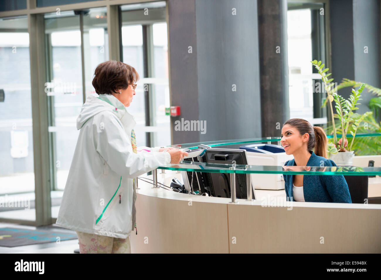 Woman discussing at reception desk Stock Photo - Alamy