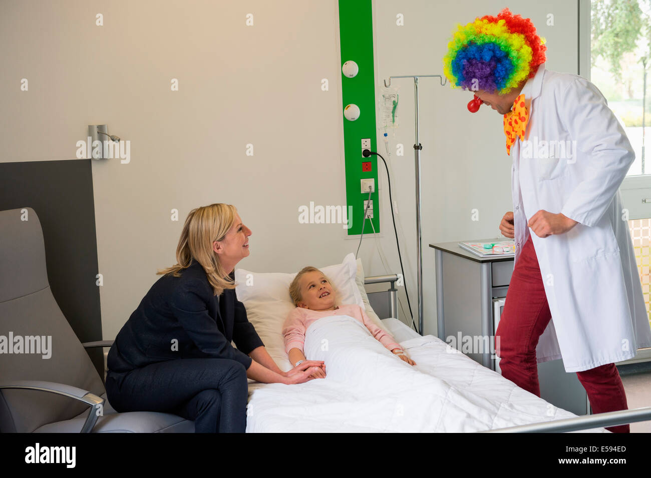 Male doctor wearing clown costume making girl patient laugh in hospital ...