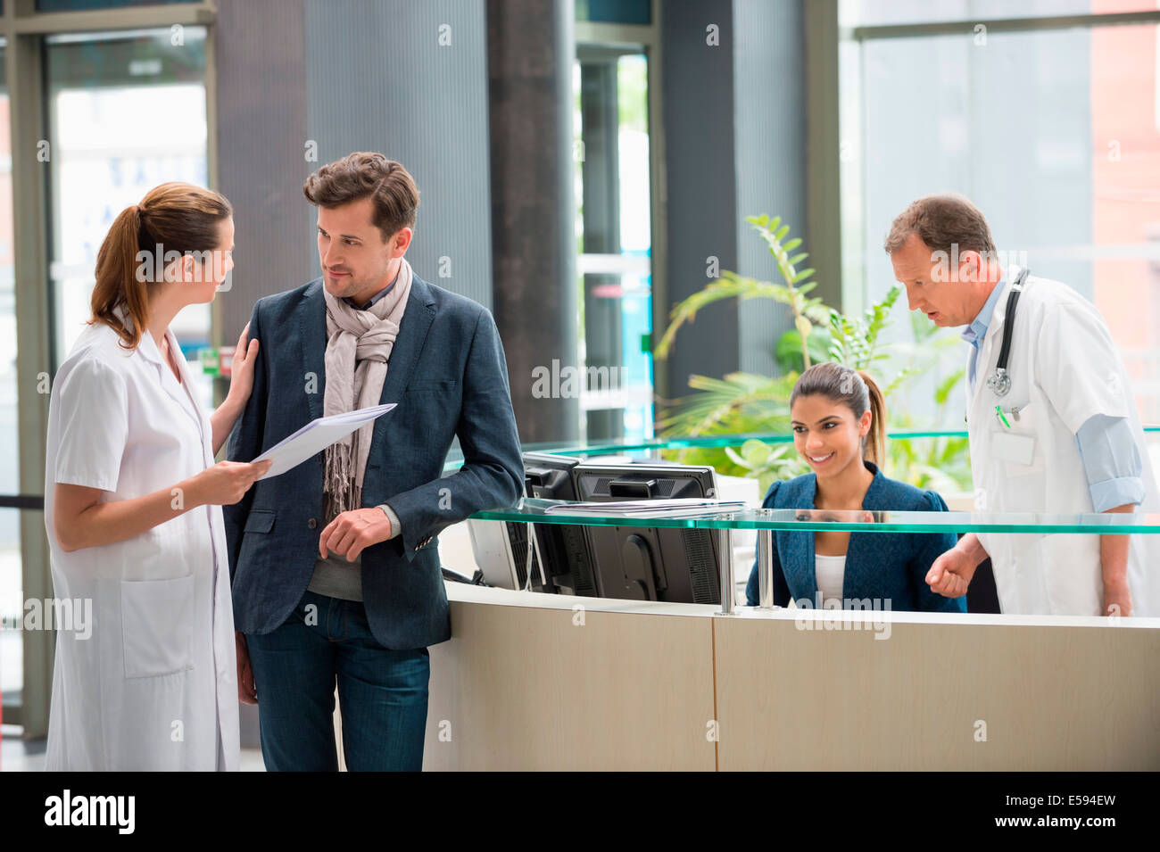 Female doctor discussing with patient at hospital reception desk Stock ...