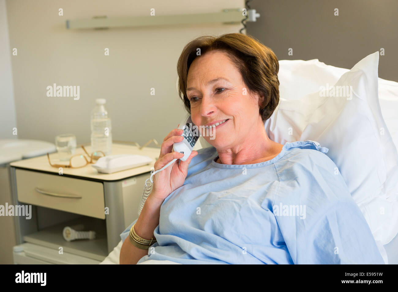 Woman talking on telephone in hospital bed Stock Photo - Alamy