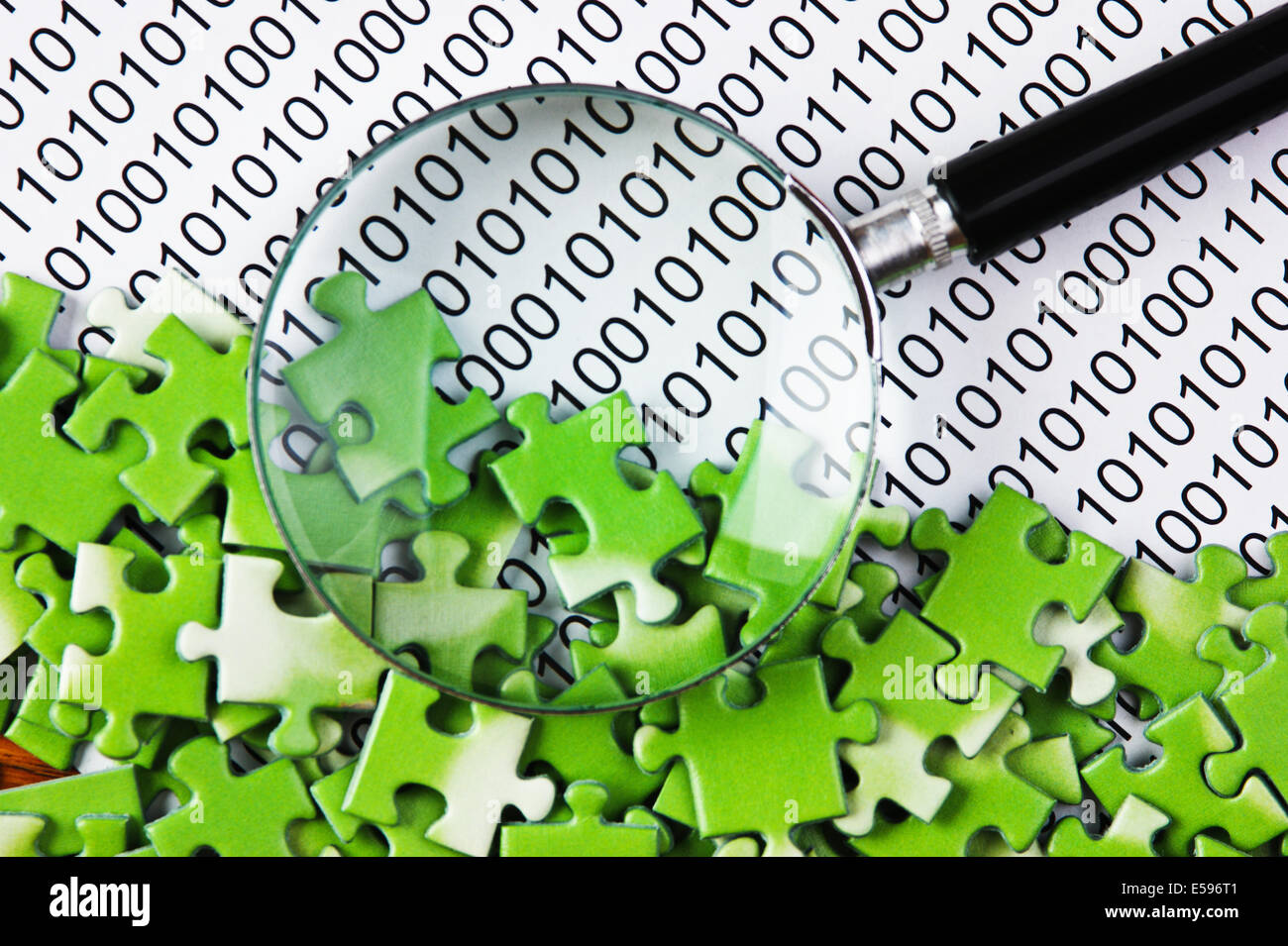puzzles and magnifying glass on a binary code Stock Photo - Alamy