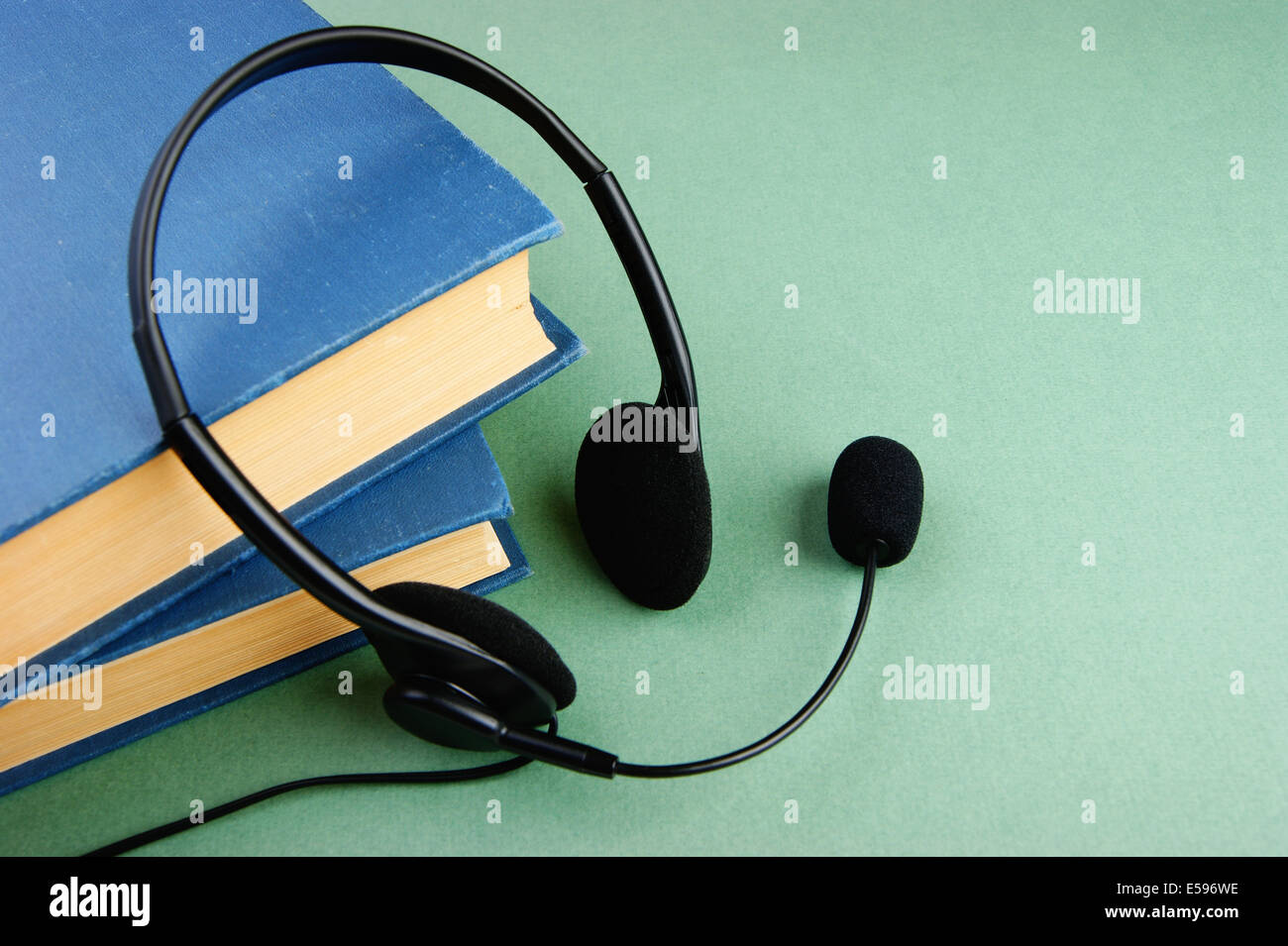 Headphones with a microphone and a stack of books on a green background ...