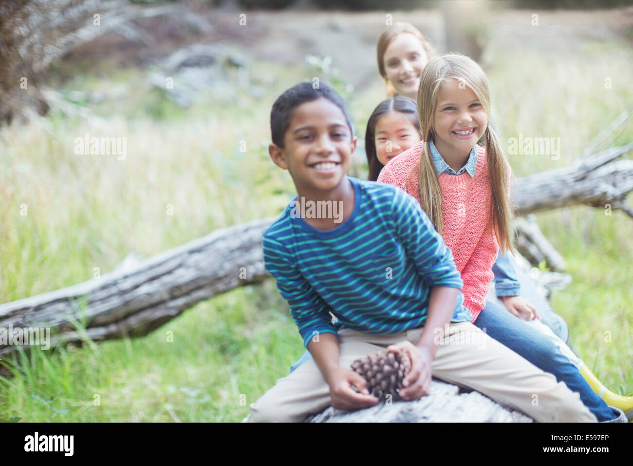 Children sitting on log in forest Stock Photo - Alamy