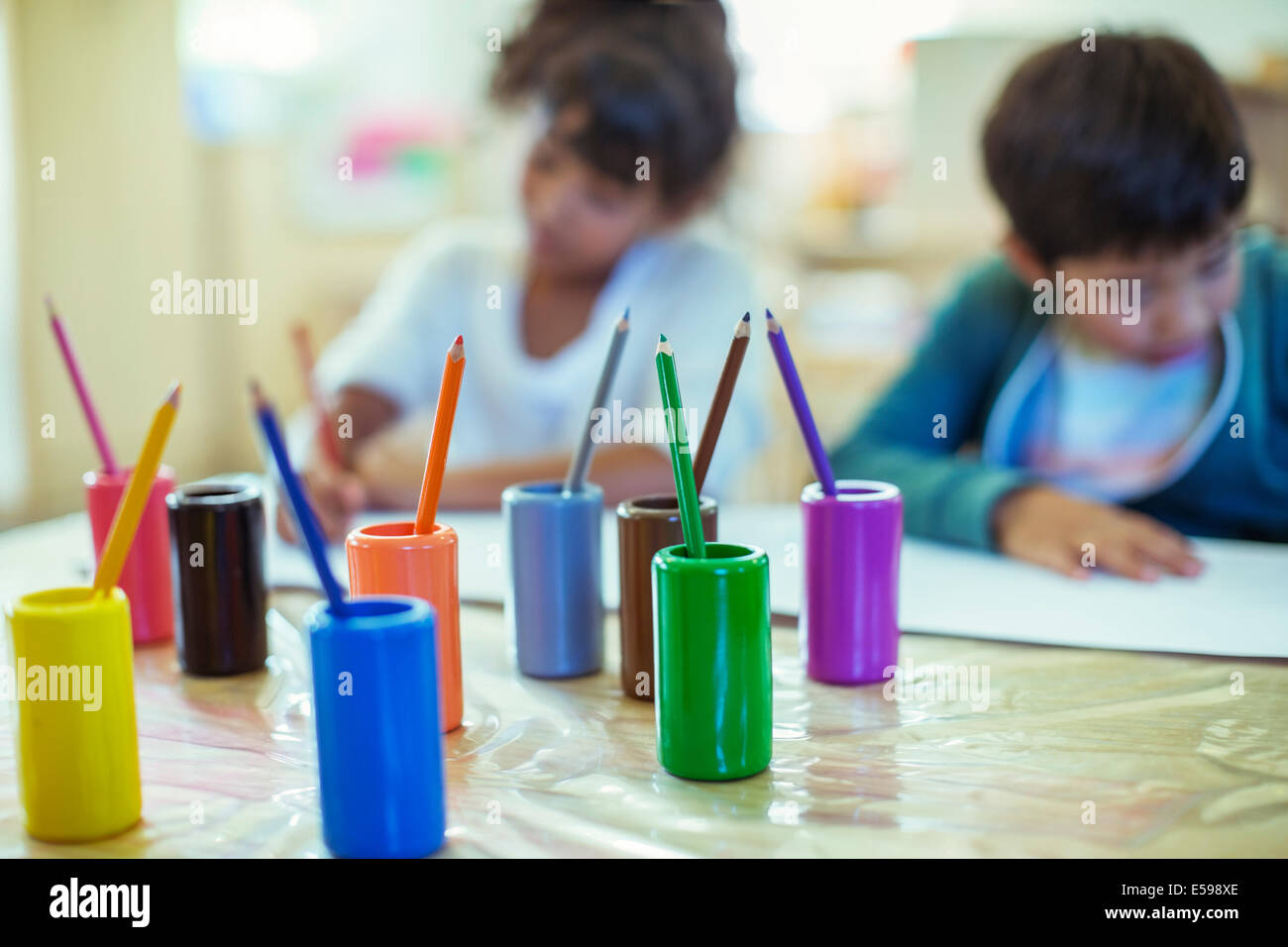 Colored pencils on desk in classroom Stock Photo - Alamy
