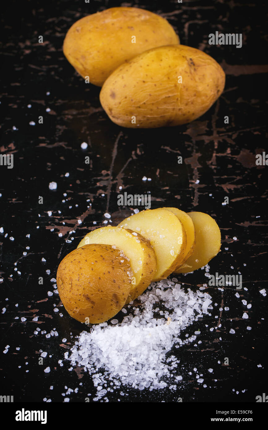 Sliced boiled potatoes with sea salt over black wooden table Stock ...