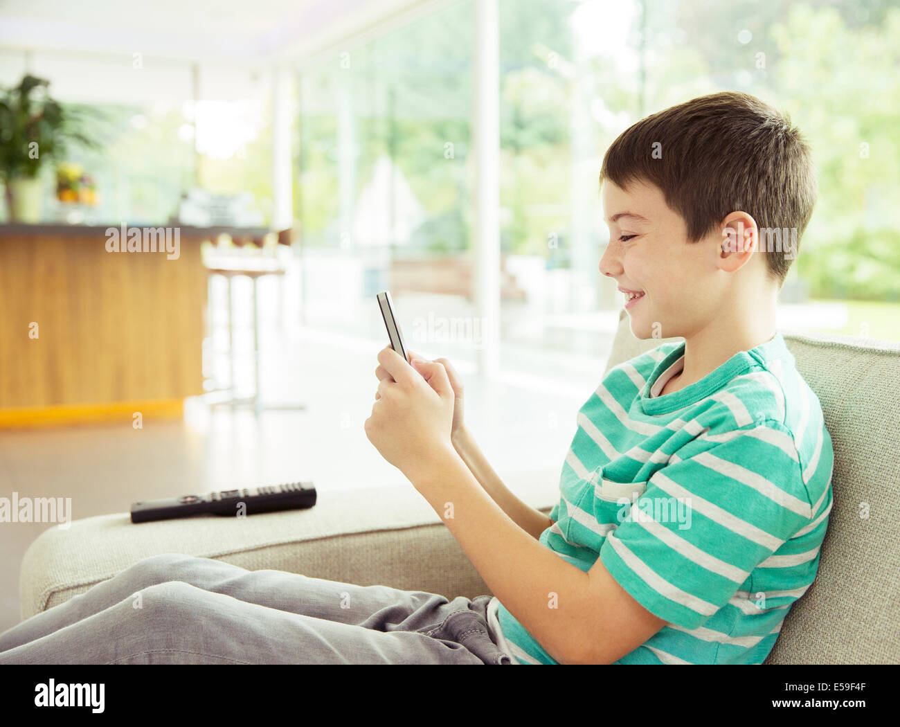 Boy using cell phone on sofa Stock Photo - Alamy