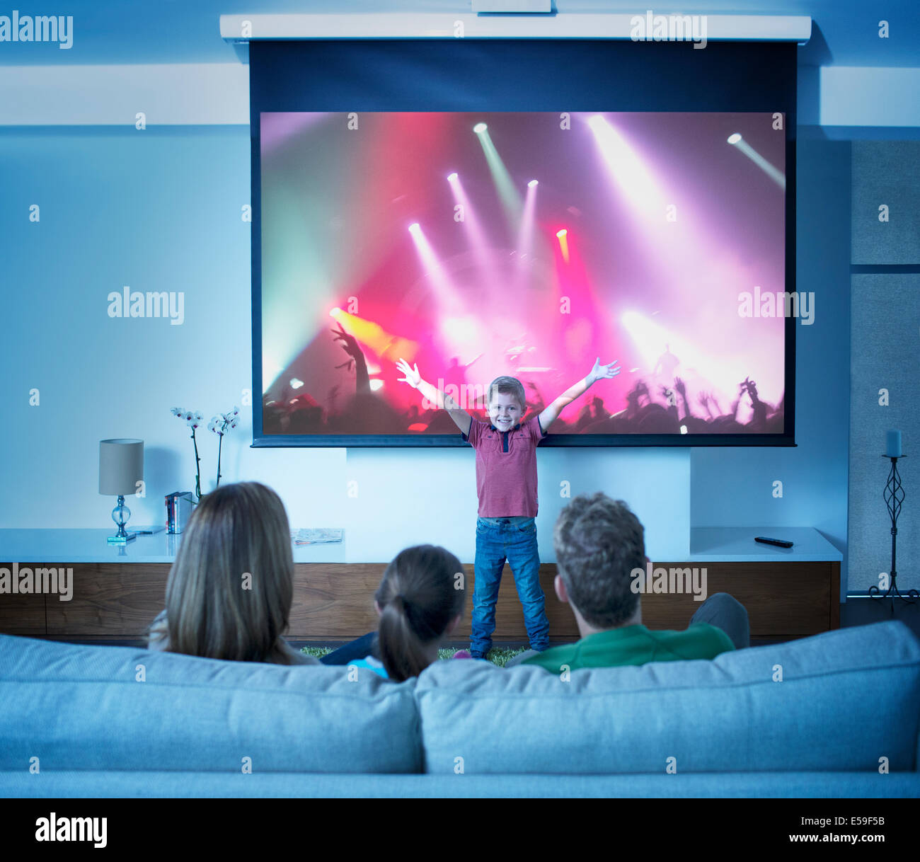 Family watching boy perform in front of concert screen Stock Photo - Alamy