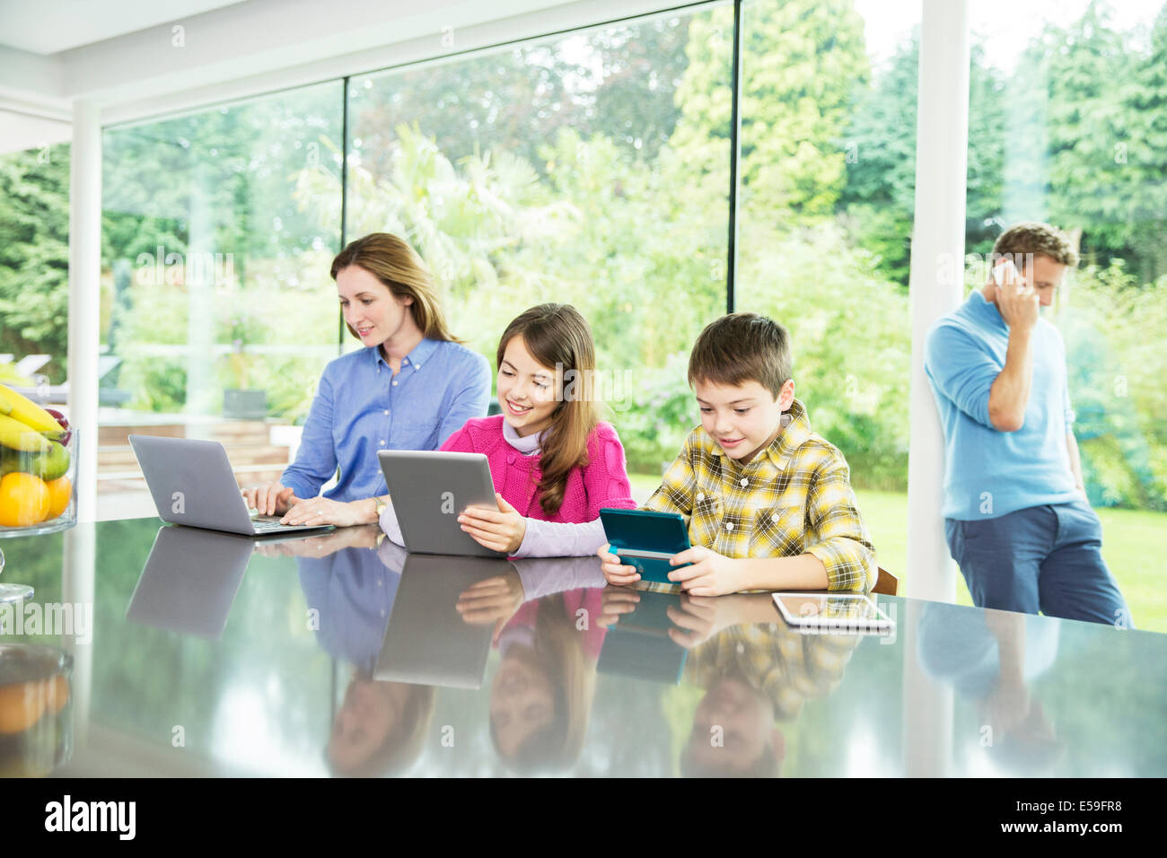 Family using technology in kitchen Stock Photo - Alamy