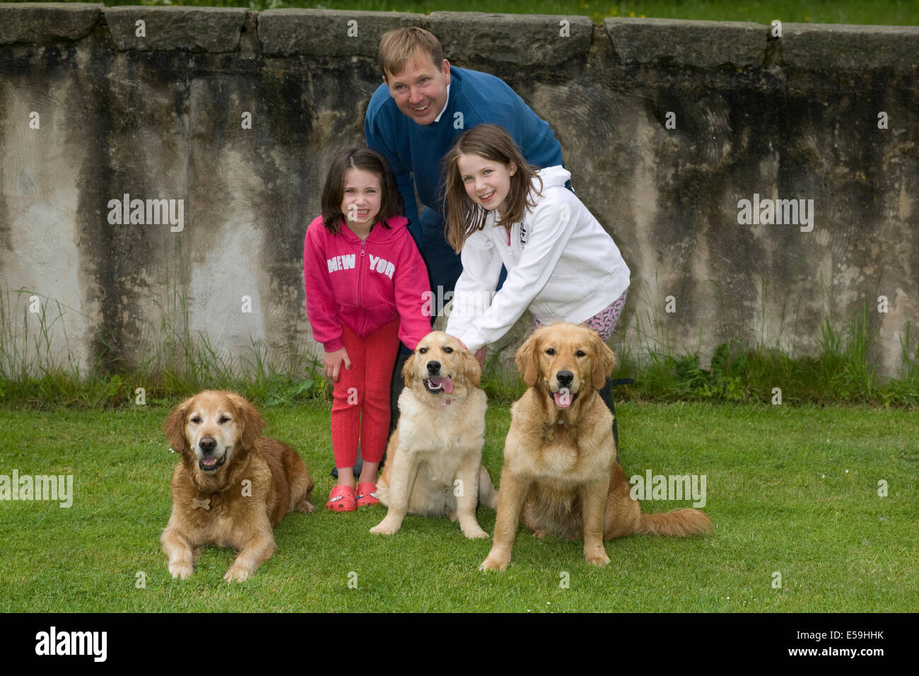Zoe a 5 month old female golden retriever puppy with her owners behind ...