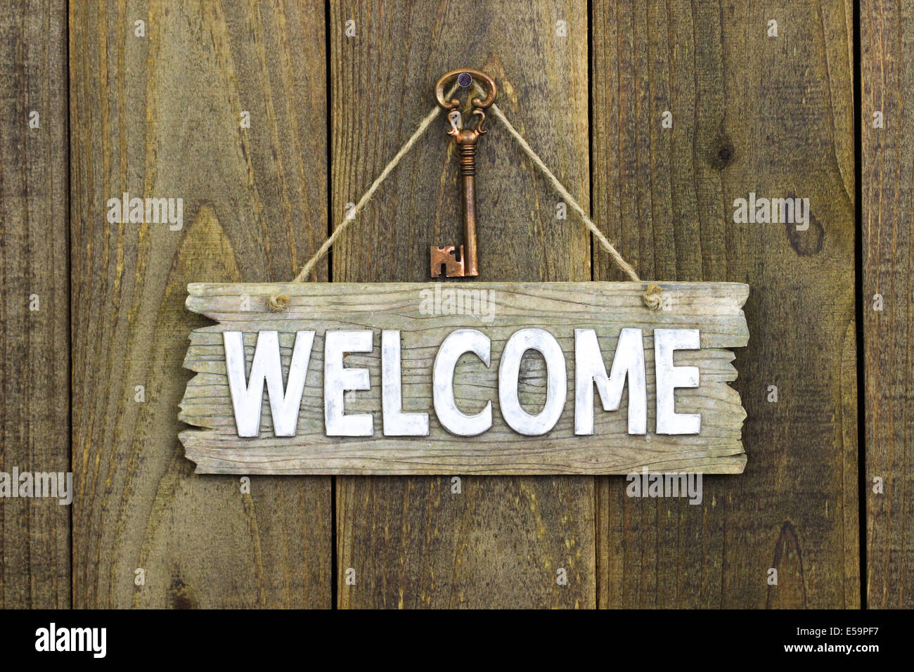 Welcome sign with bronze skeleton key hanging on rustic wooden fence ...