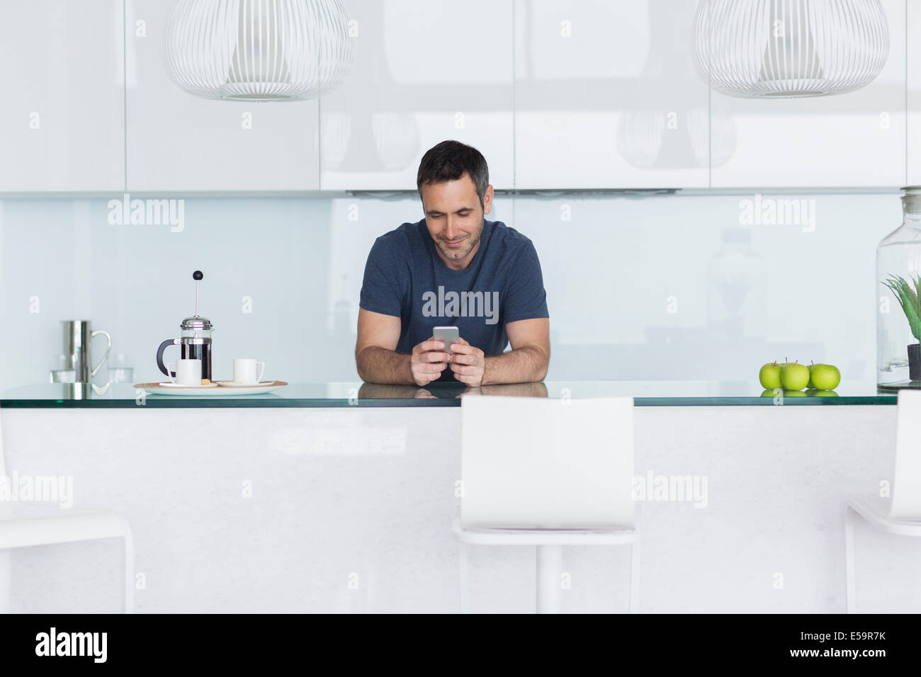 Man using cell phone in modern kitchen Stock Photo - Alamy