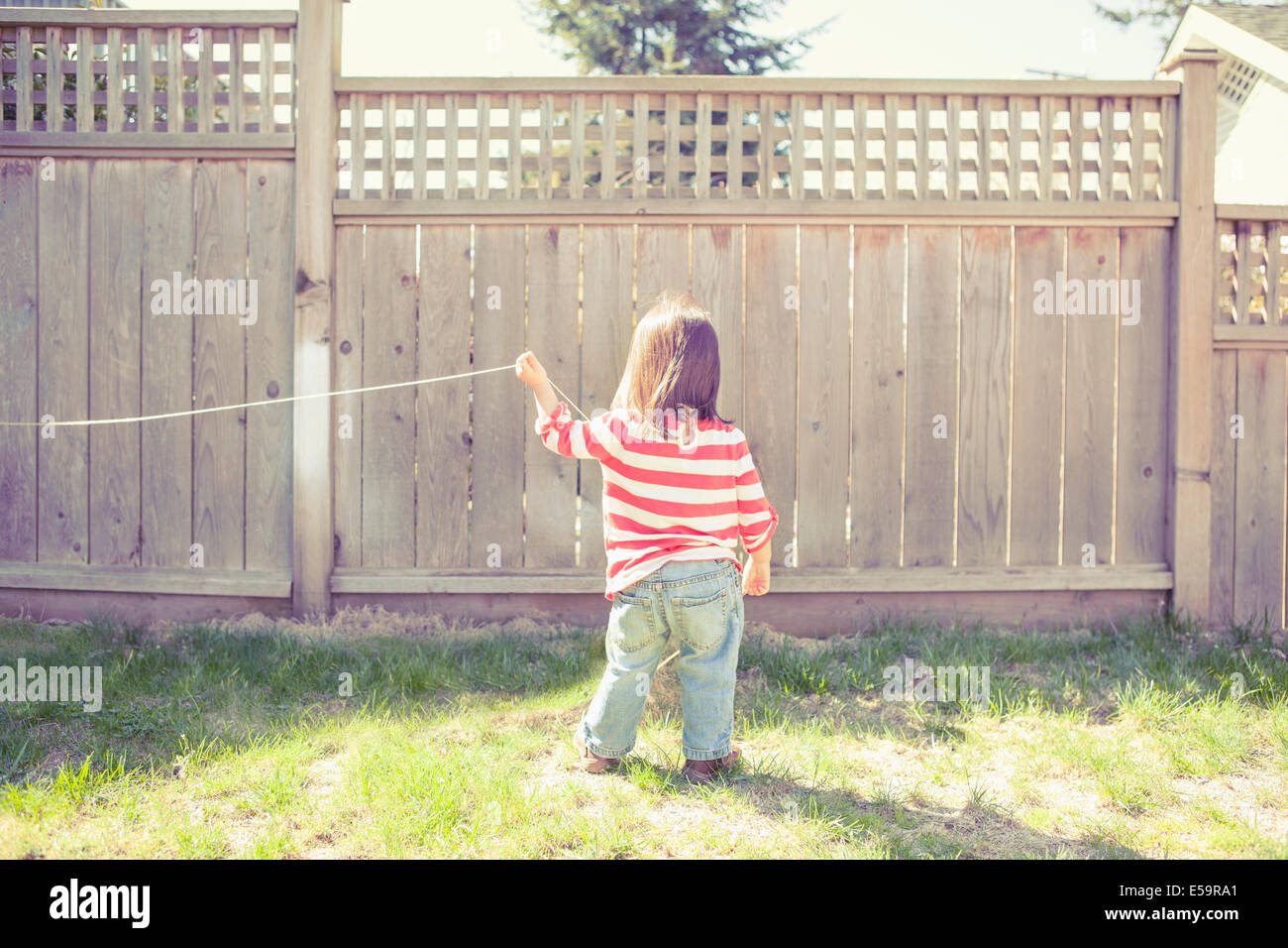 Baby girl playing with string in backyard Stock Photo - Alamy
