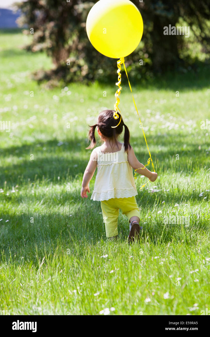 Girl carrying balloon in backyard Stock Photo - Alamy
