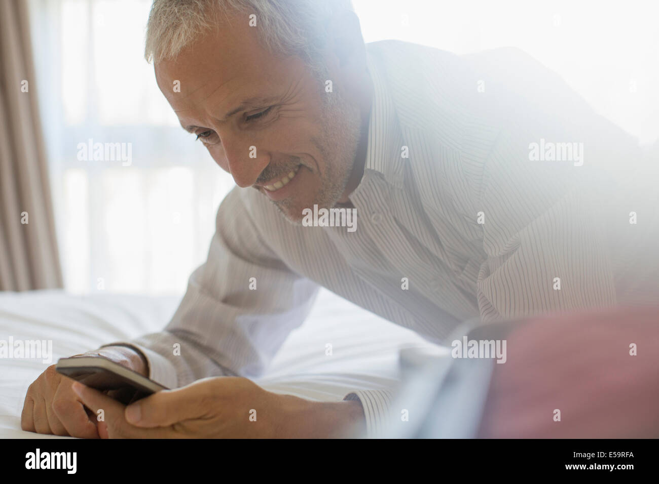 Businessman using cell phone on bed in hotel room Stock Photo - Alamy