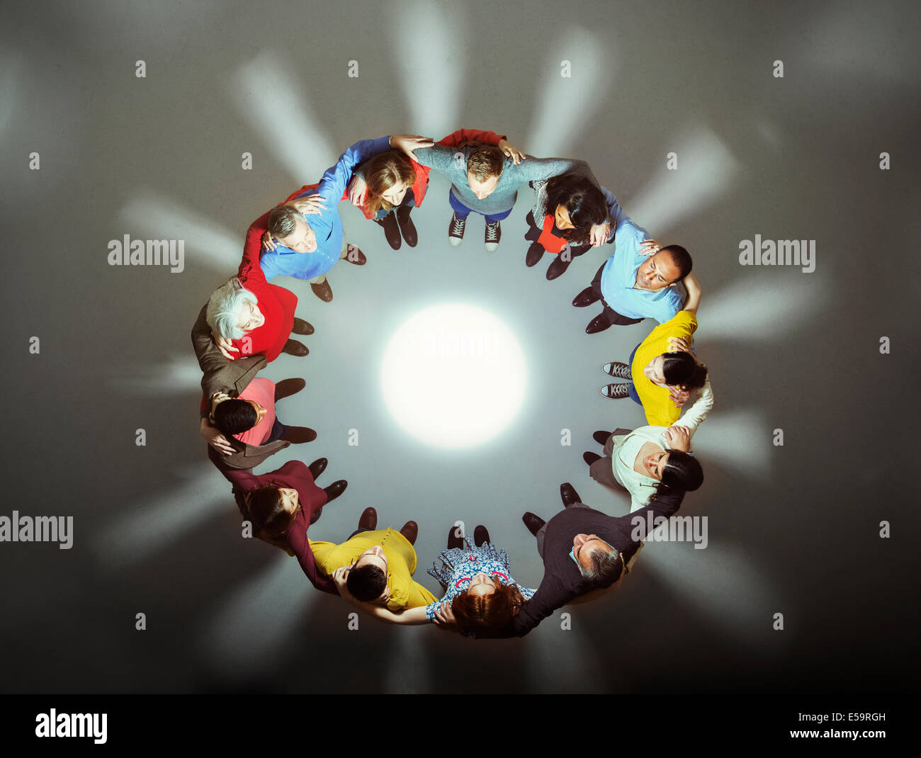 Diverse group around bright light Stock Photo - Alamy