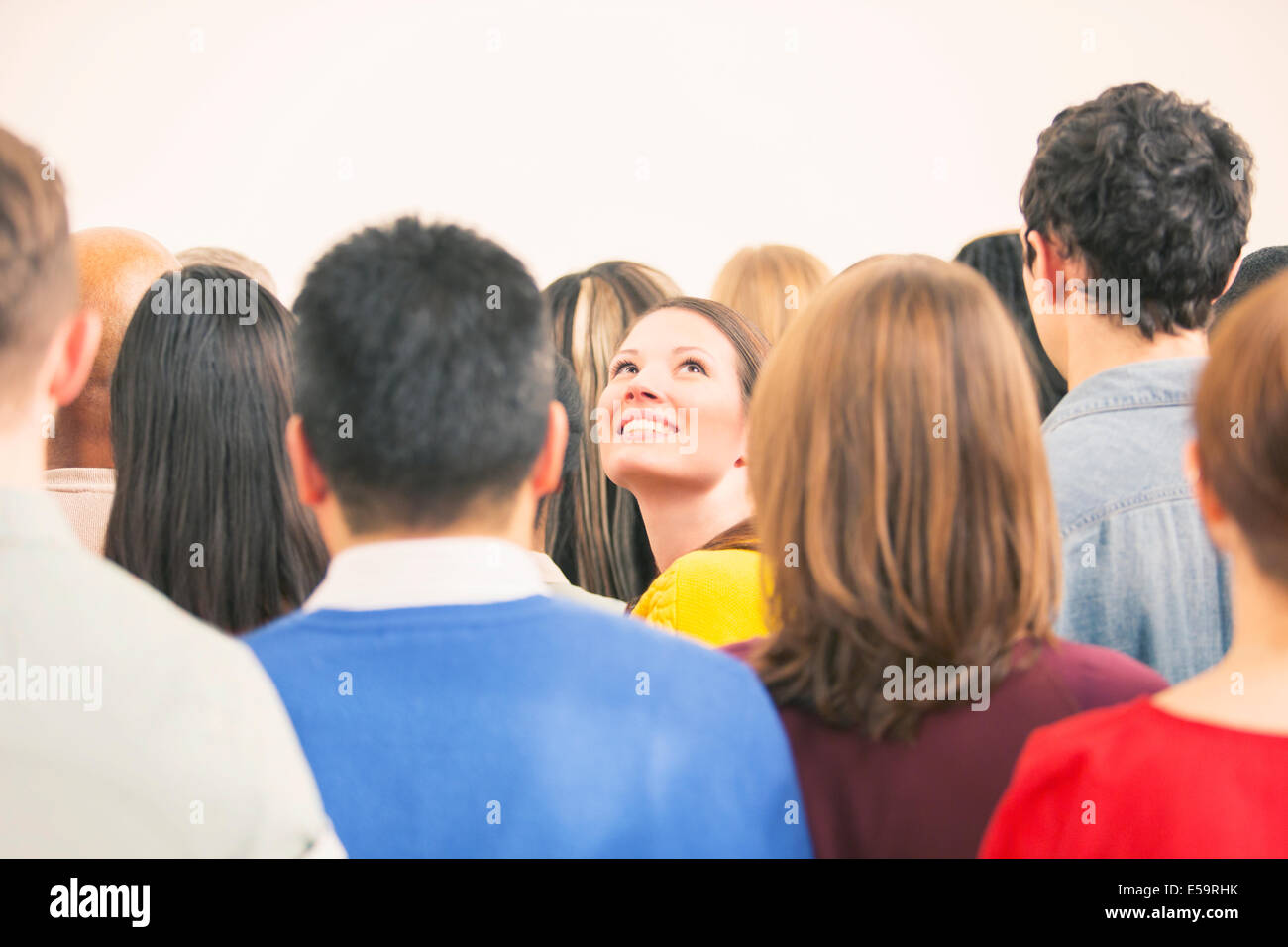 Confident woman looking up in crowd Stock Photo - Alamy