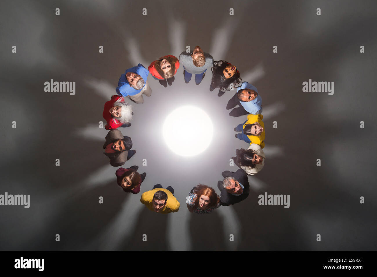 Business people around bright light Stock Photo - Alamy