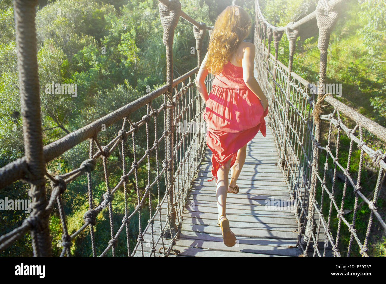Woman walking on wooden rope bridge Stock Photo - Alamy