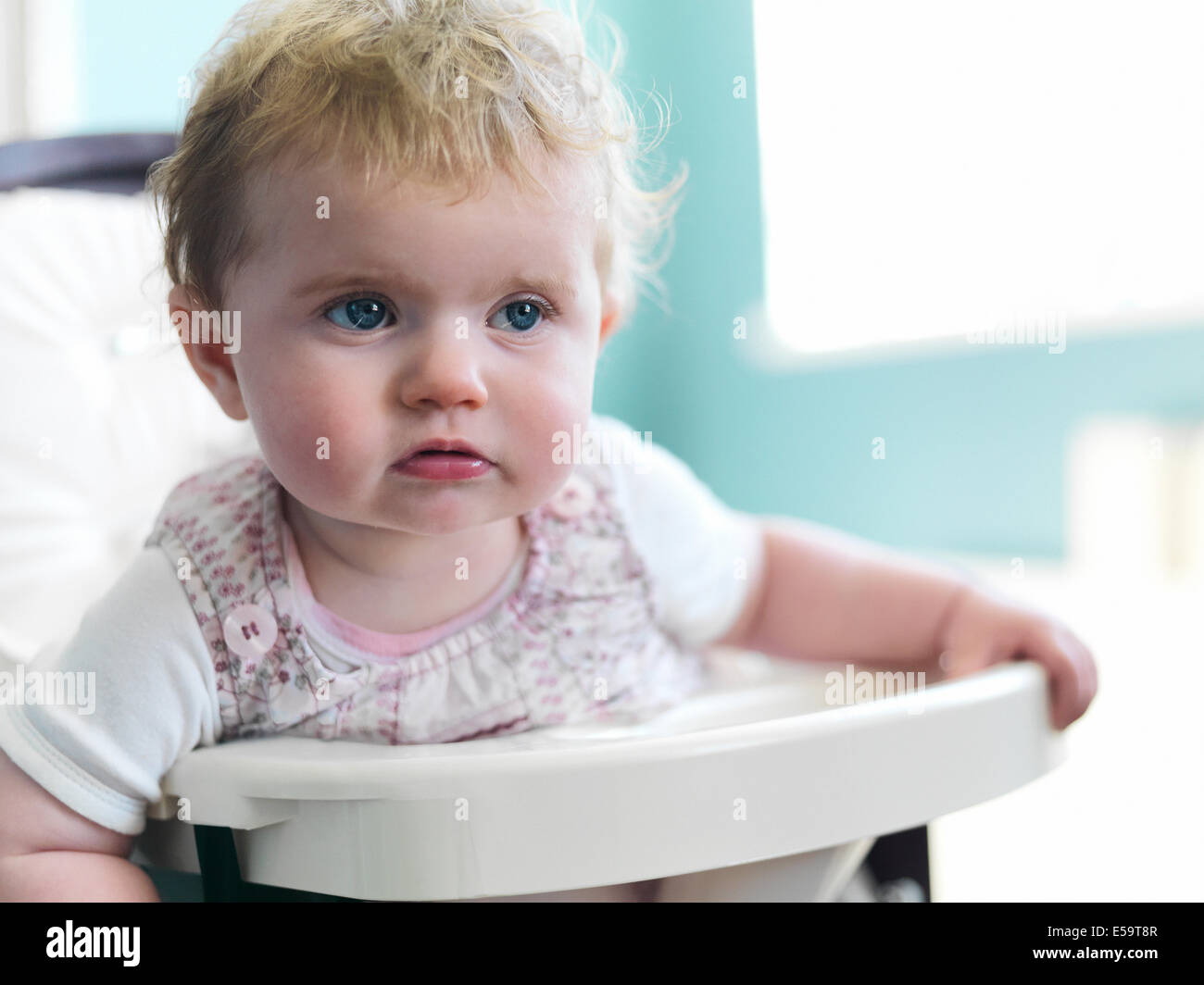Girl sitting in high chair Stock Photo - Alamy