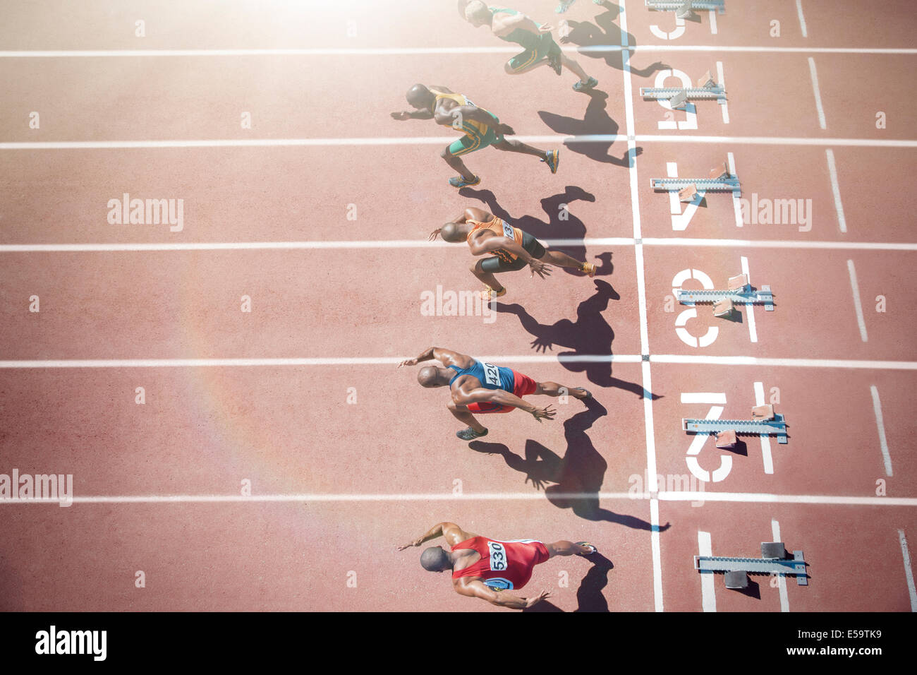 Runners taking off from starting blocks on track Stock Photo - Alamy