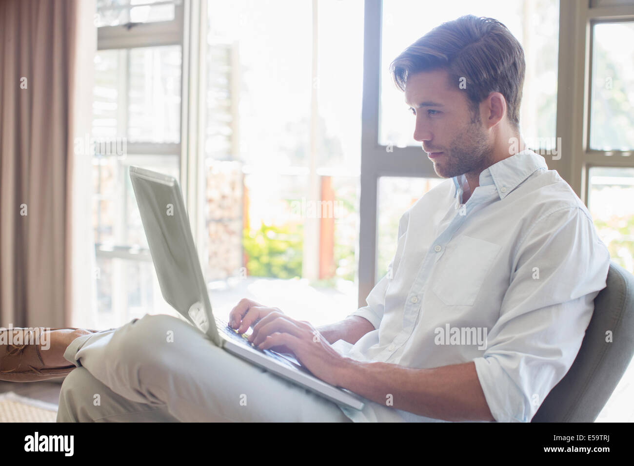 Man using laptop in living room Stock Photo - Alamy