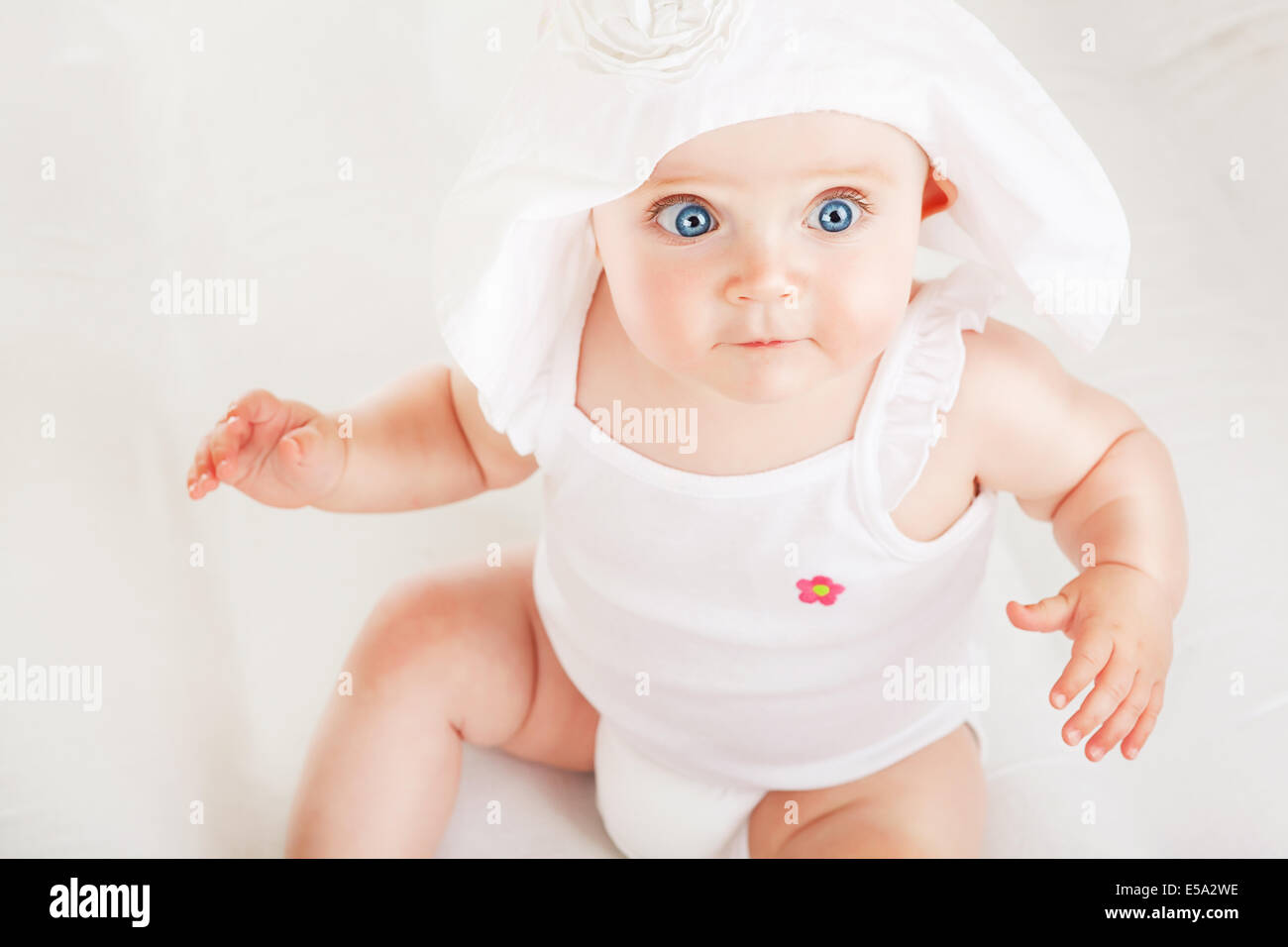 funny child on white fabric in white hat Stock Photo - Alamy