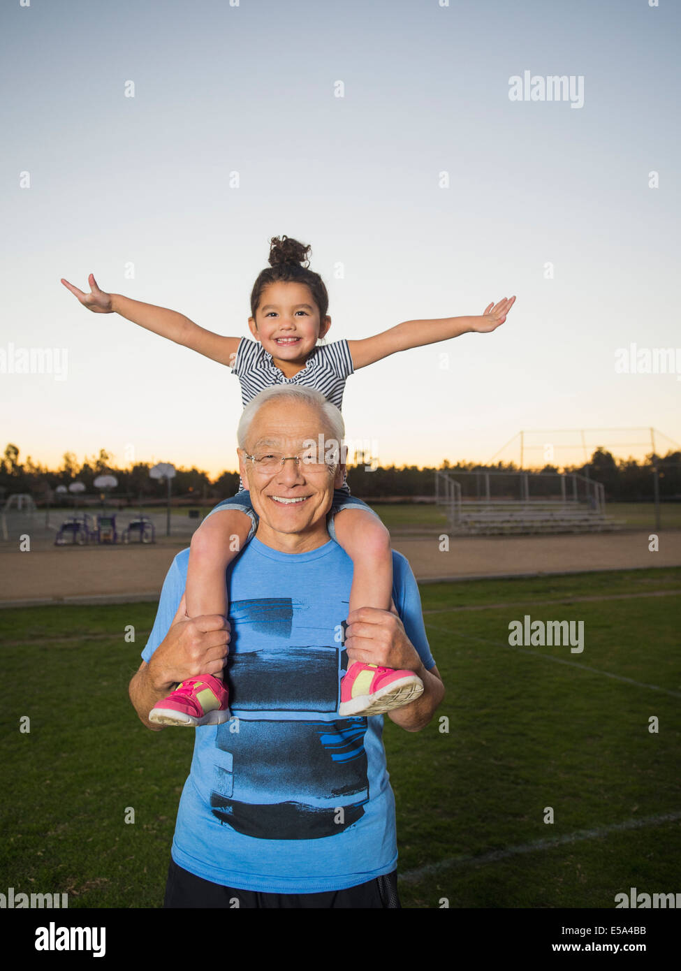 Older man carrying granddaughter on shoulders in park Stock Photo - Alamy