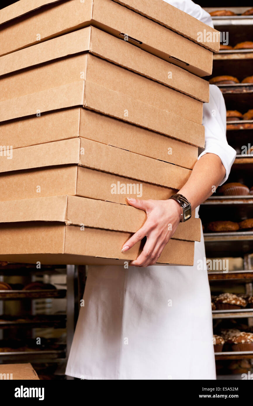 Hispanic baker carrying stack of boxes in bakery Stock Photo - Alamy