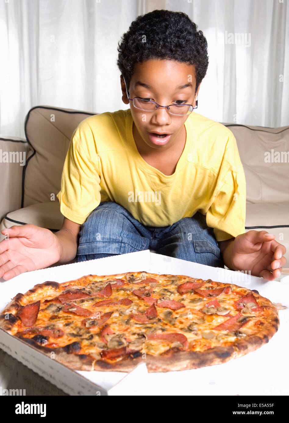 Mixed race boy admiring pizza in living room Stock Photo - Alamy