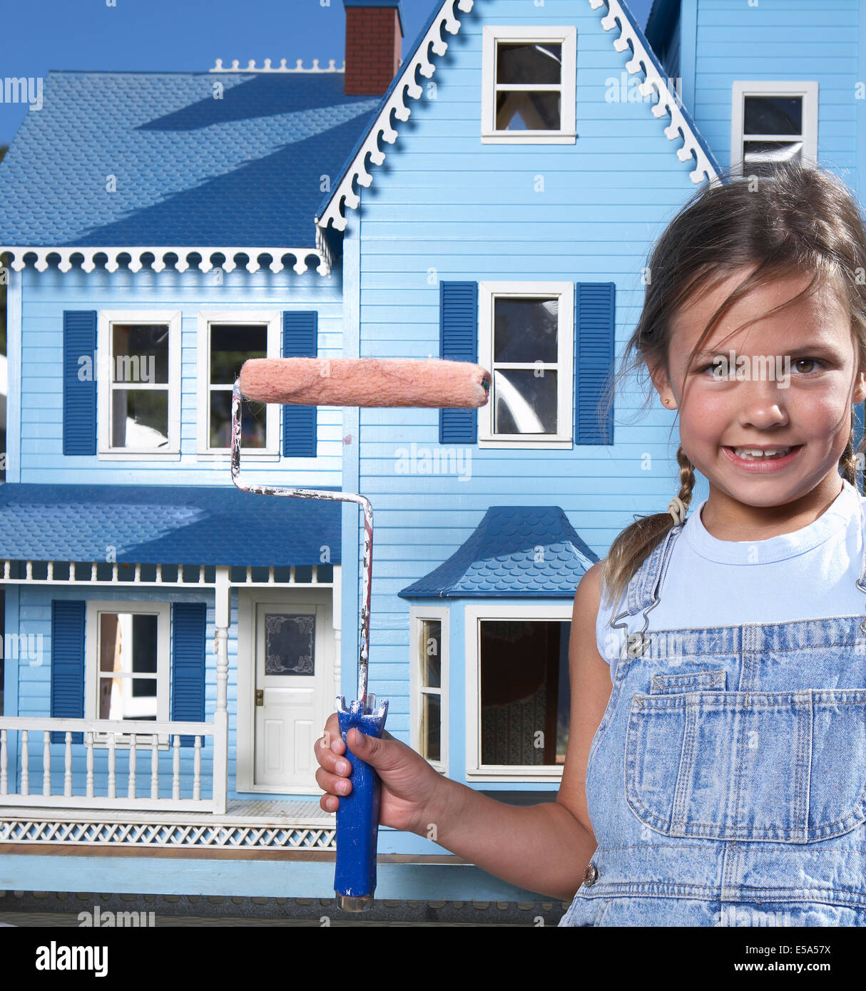 Mixed race girl painting doll house Stock Photo - Alamy