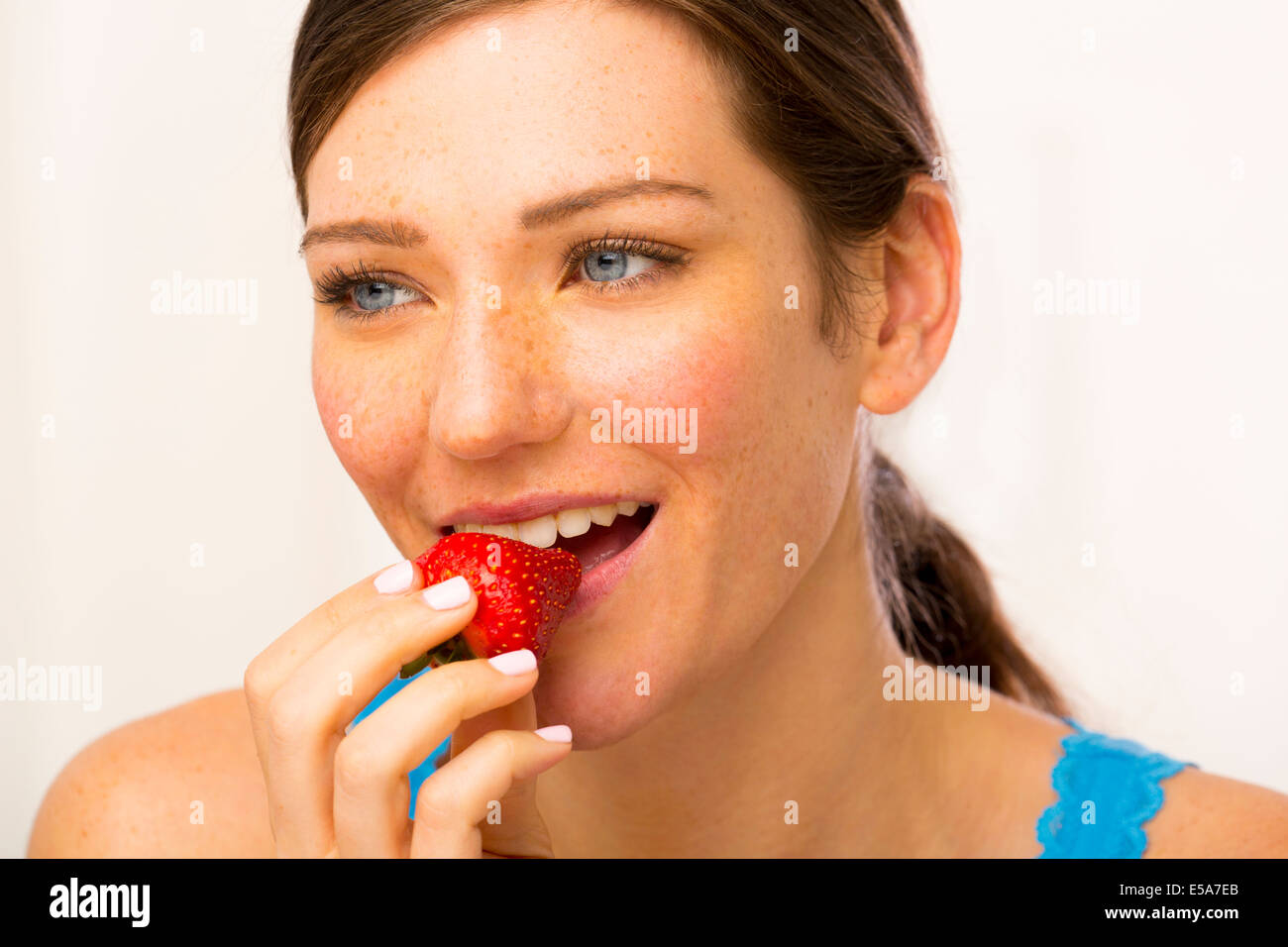 Caucasian woman eating strawberry Stock Photo - Alamy