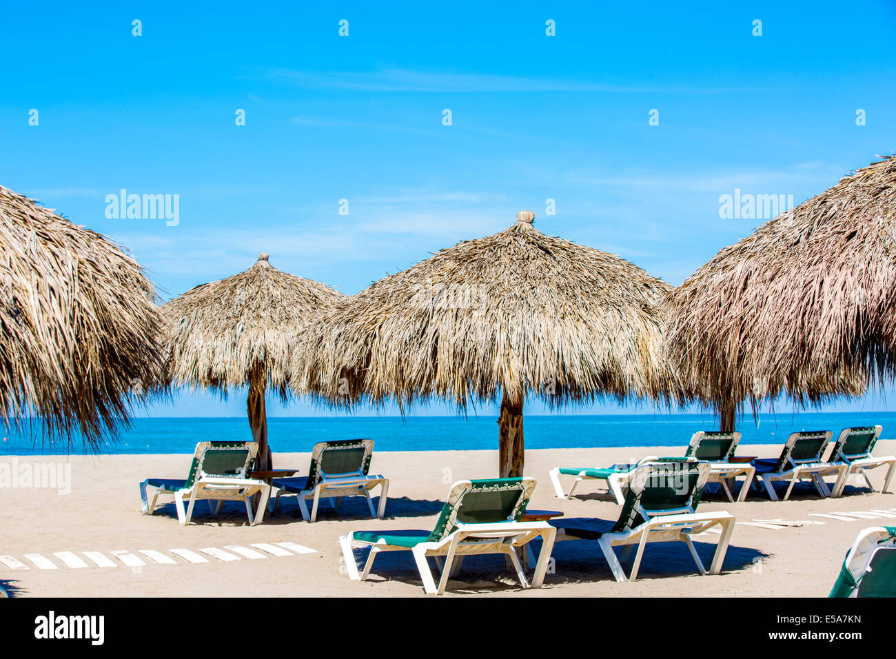 Lounge chairs and thatch umbrellas on tropical beach Stock Photo - Alamy