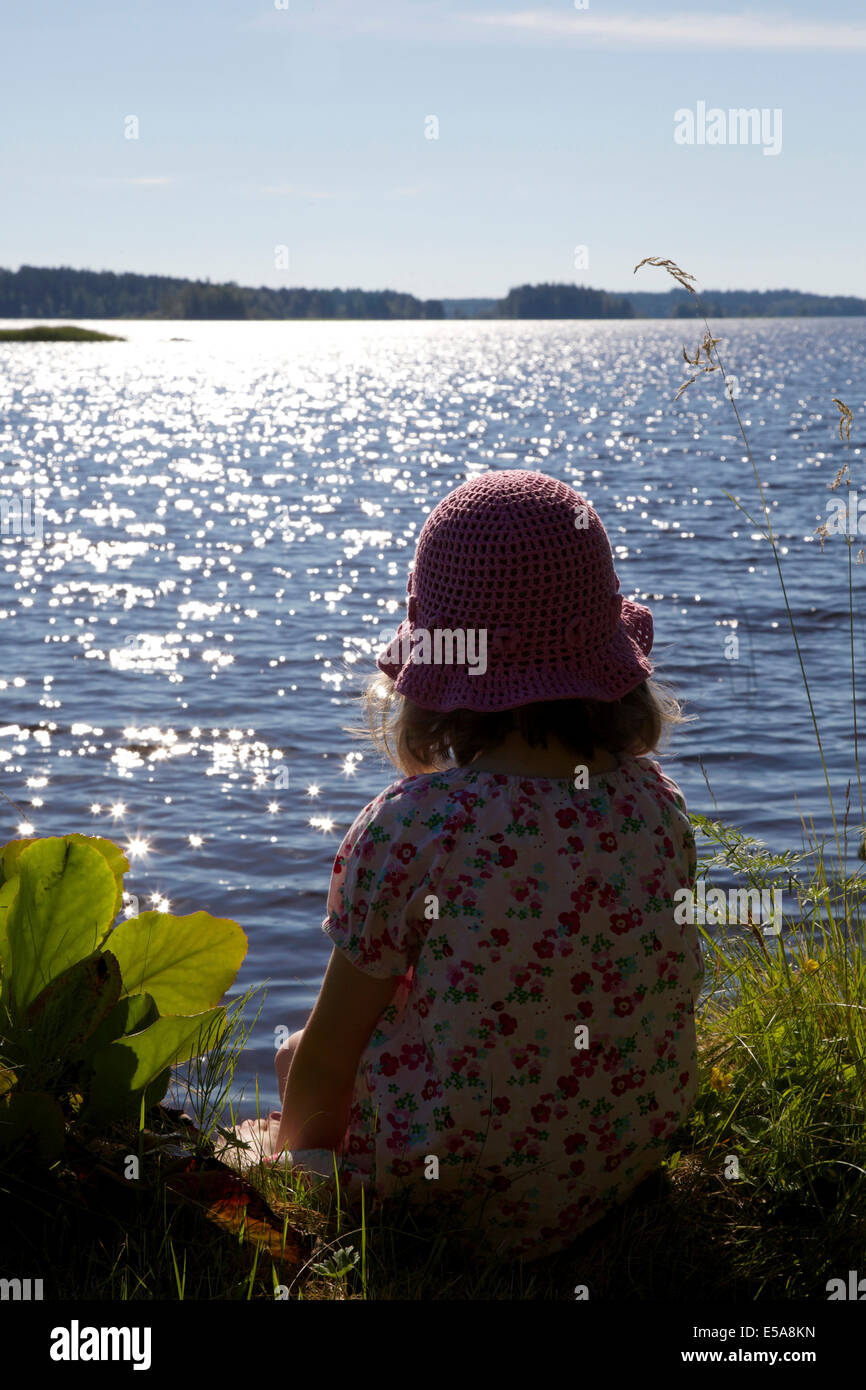 Girl sitting at lakeside in summer in Finland Stock Photo - Alamy