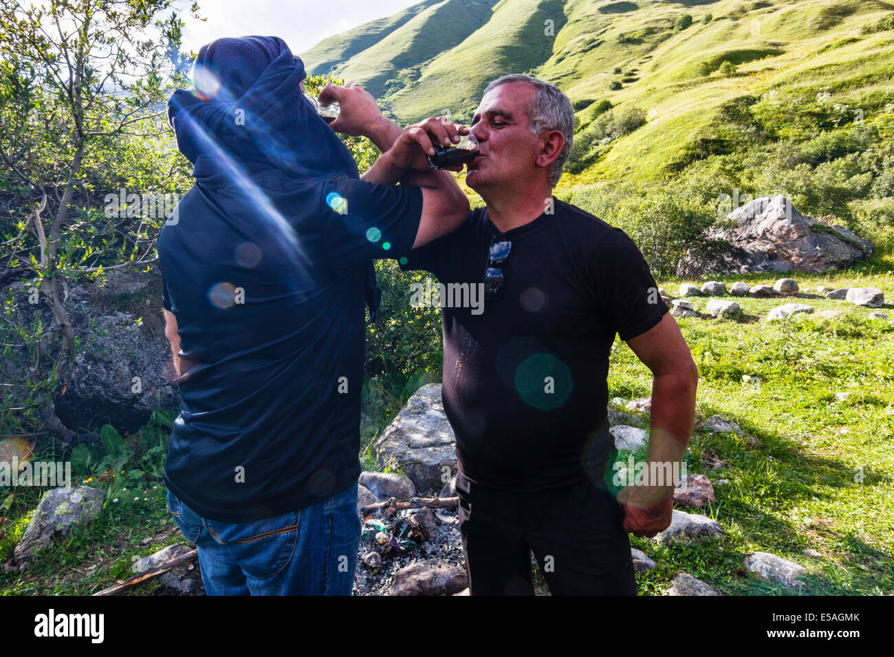 Georgian men toasting and drinking wine at Enguri valley near Ushguli ...