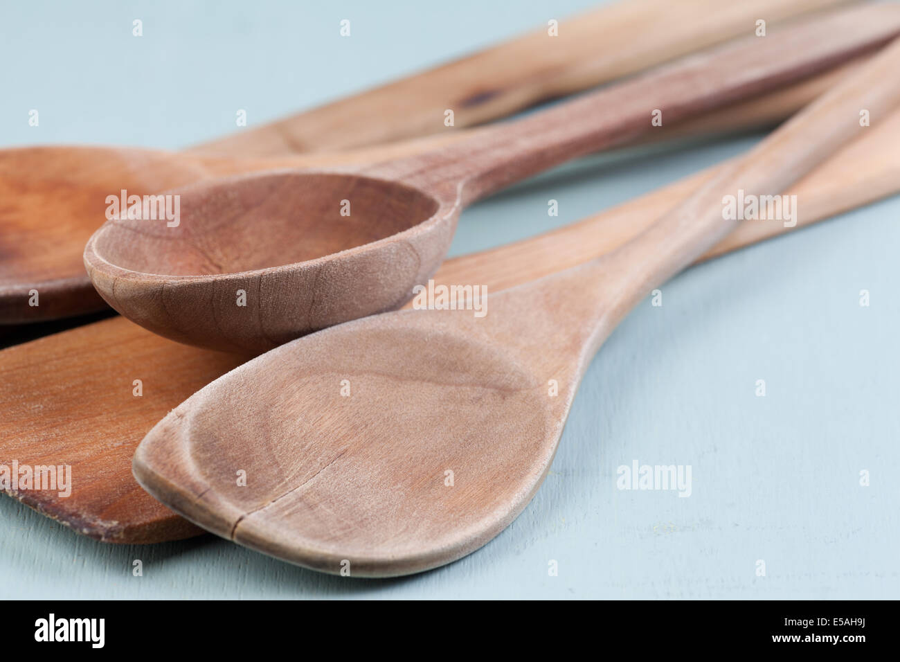 used wooden spoons on light blue table Stock Photo - Alamy