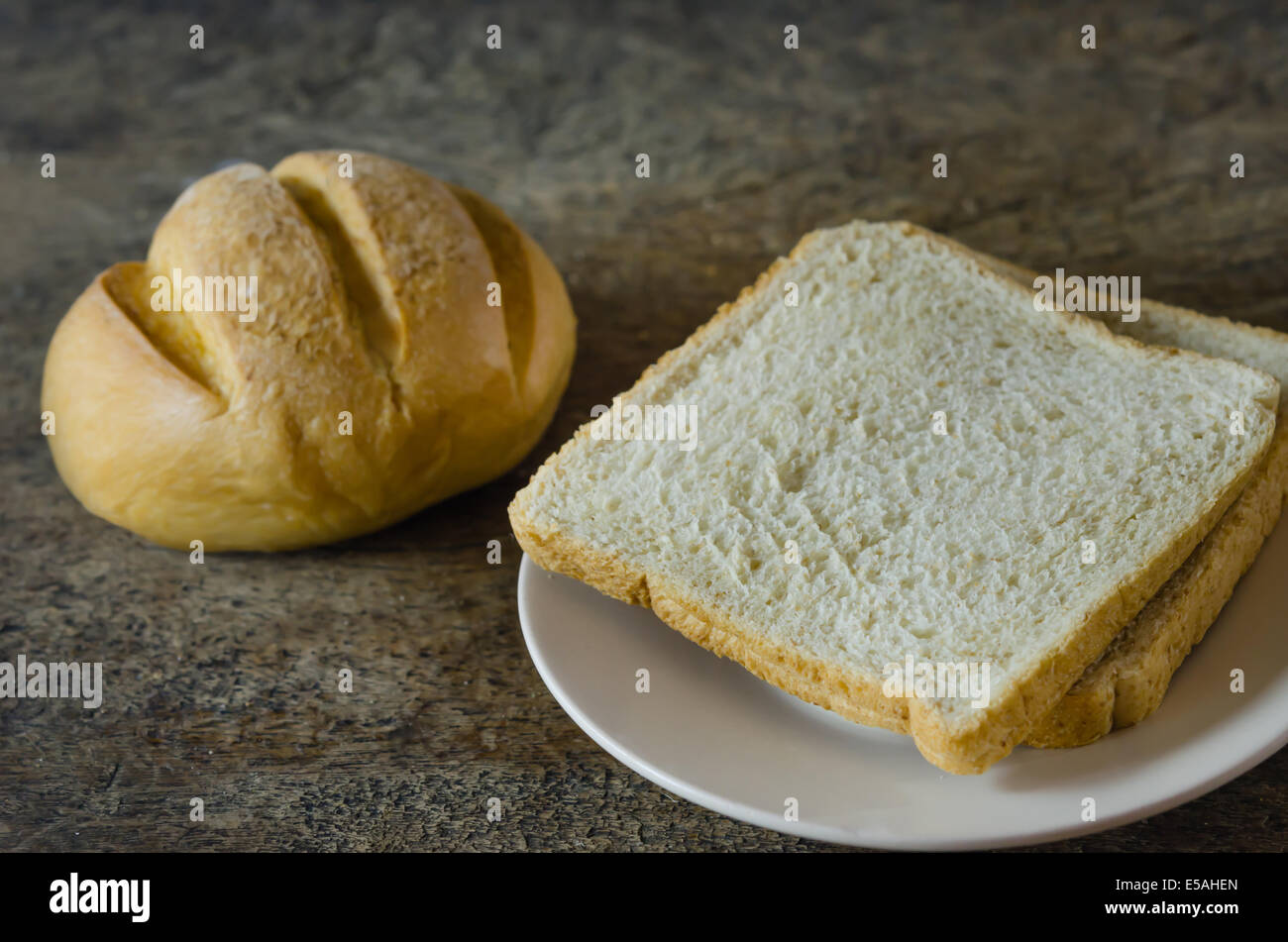 fresh bun and slice bread on dish over wooden background Stock Photo ...