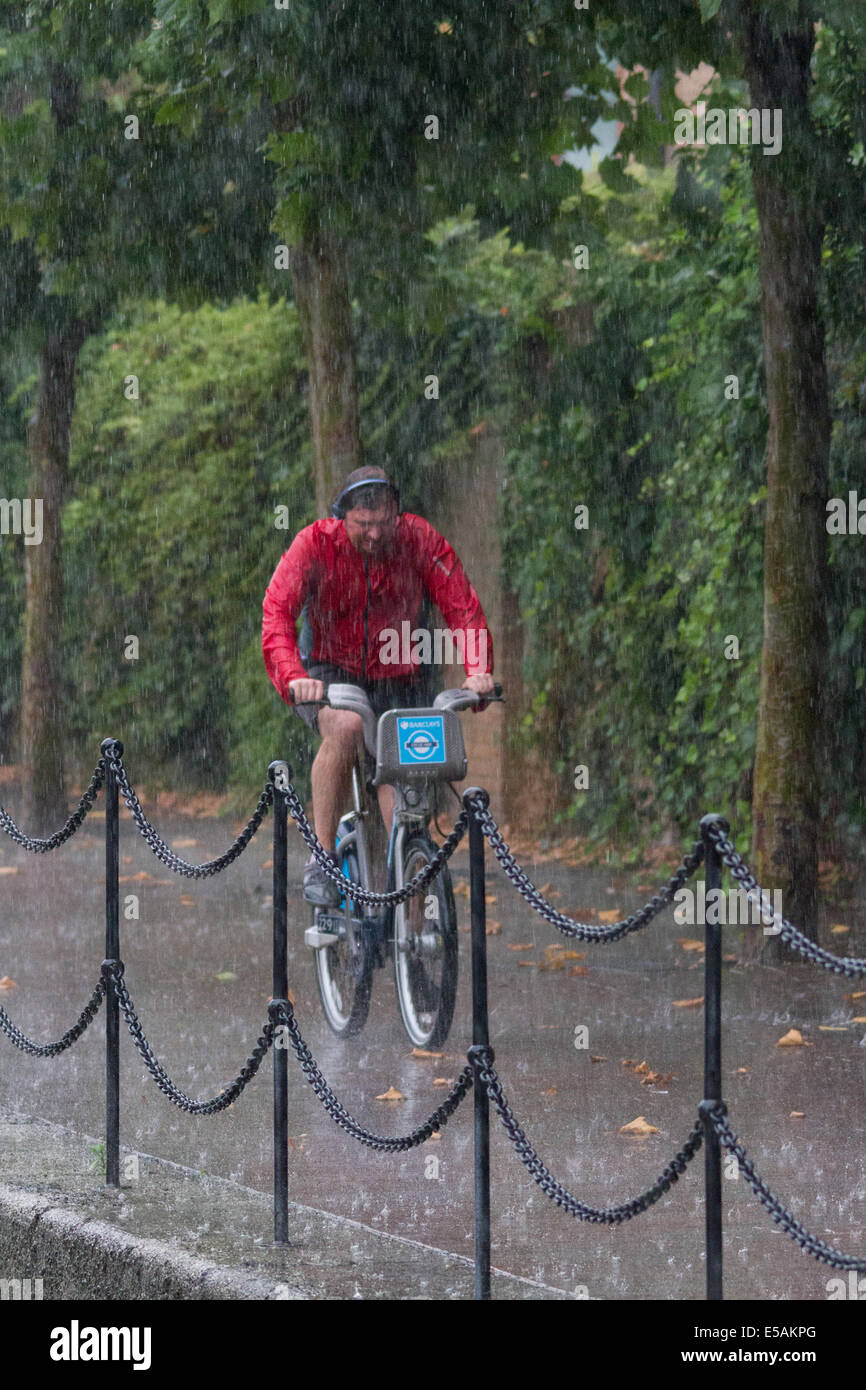 Man wearing red jacket riding a Barclay's 'Boris' bike in torrential ...