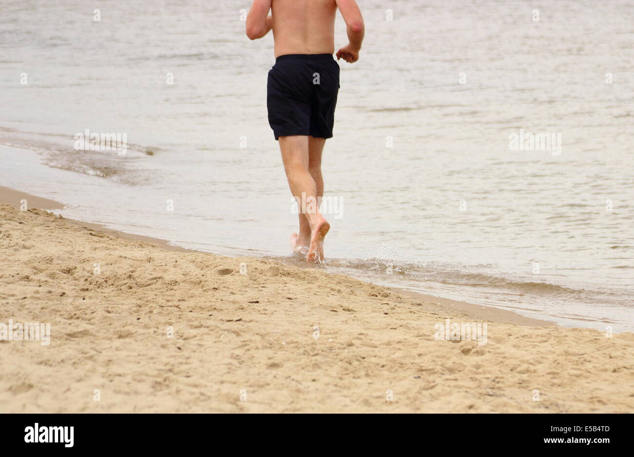 Trail running. Man running on the seafront on the beach in summer Stock ...