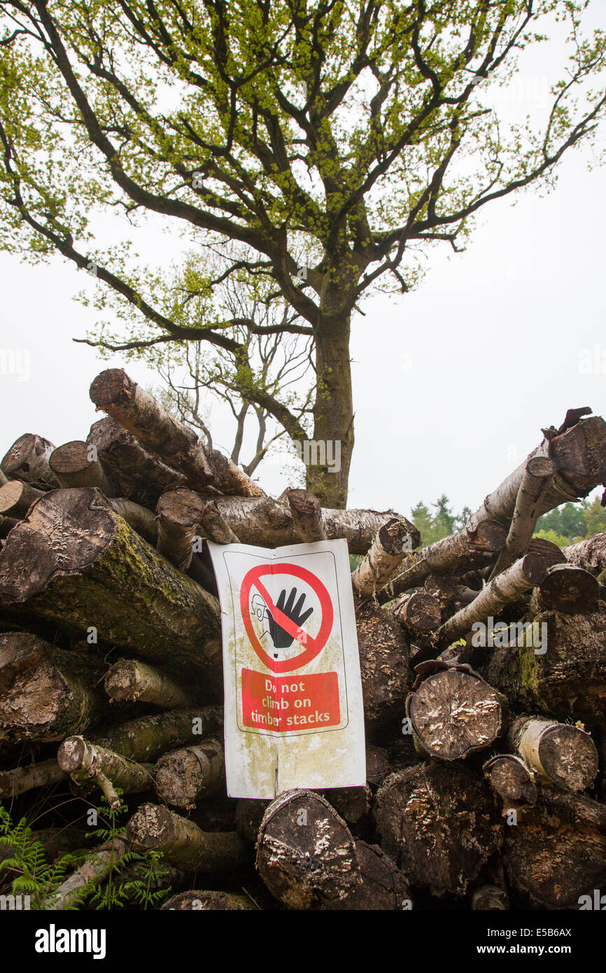 Warning sign against climbing, fixed to a stack of logs in a woodland ...