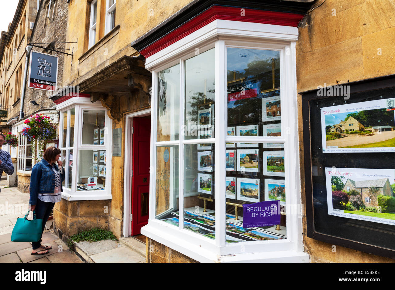 Cotswolds estate agents store customer looking through window selling ...