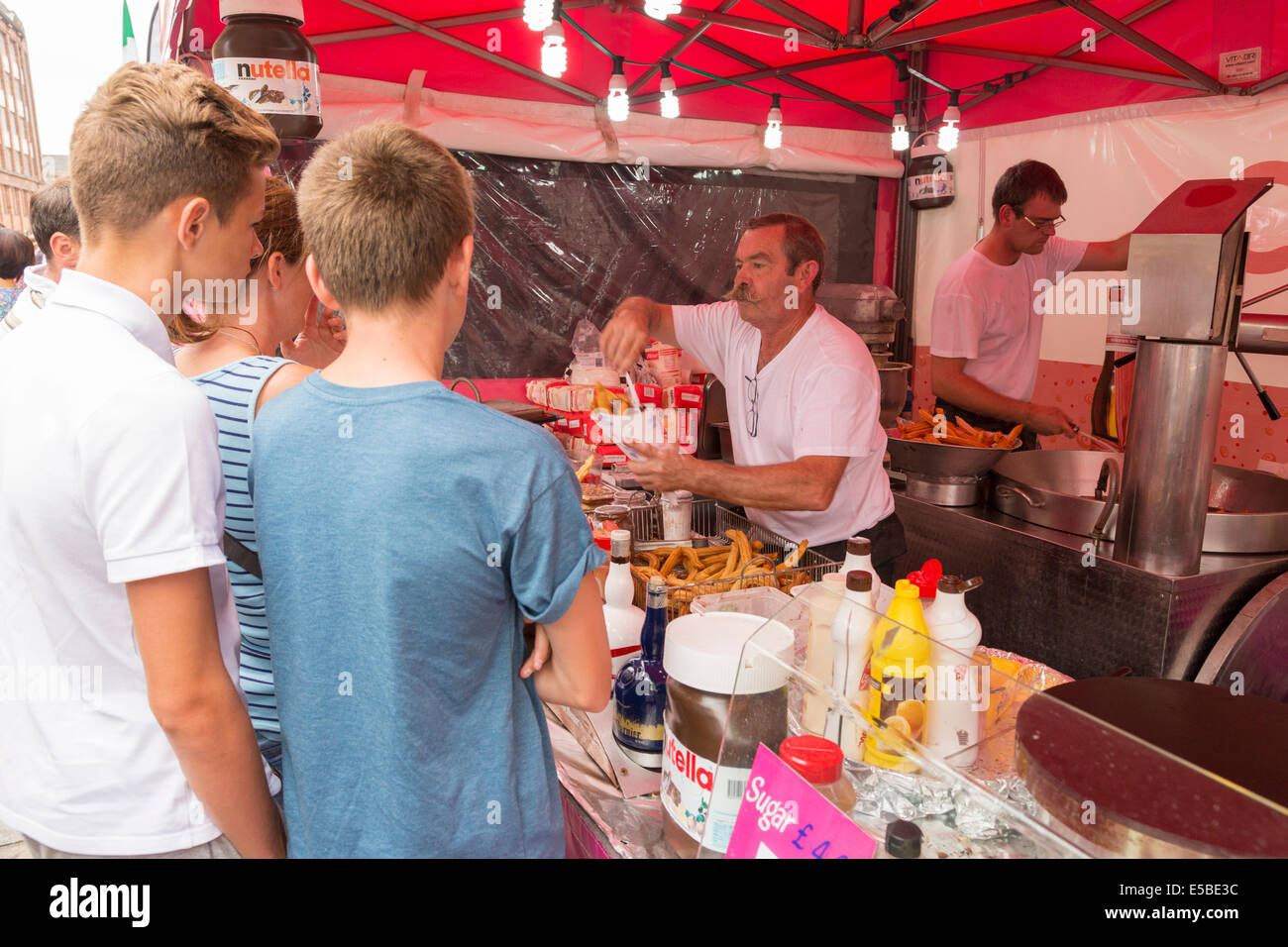 A man serves food to customers in an outdoor eating place/stall, West ...