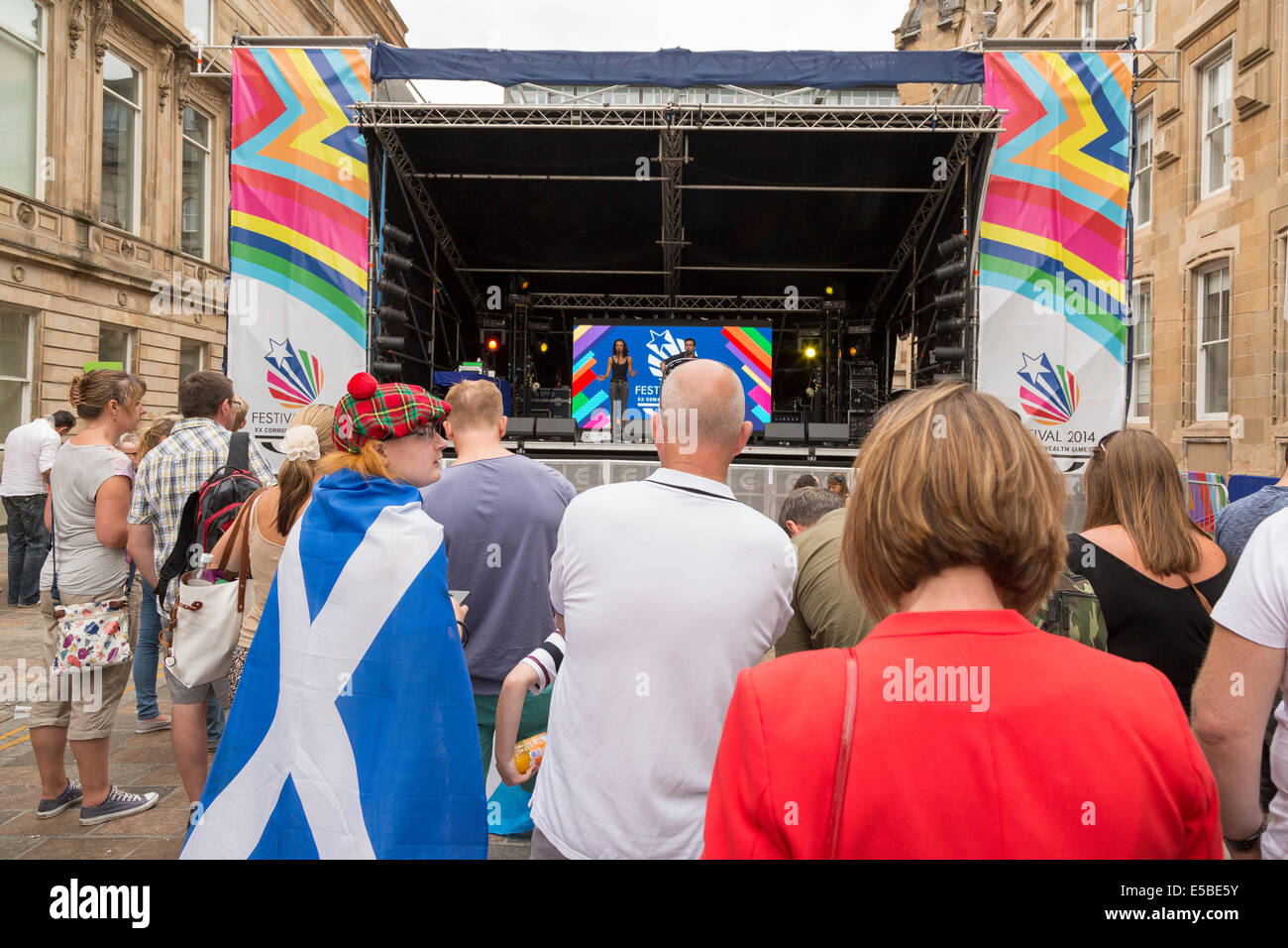 Boy with Scottish flag draped over his shoulders watches a performance ...