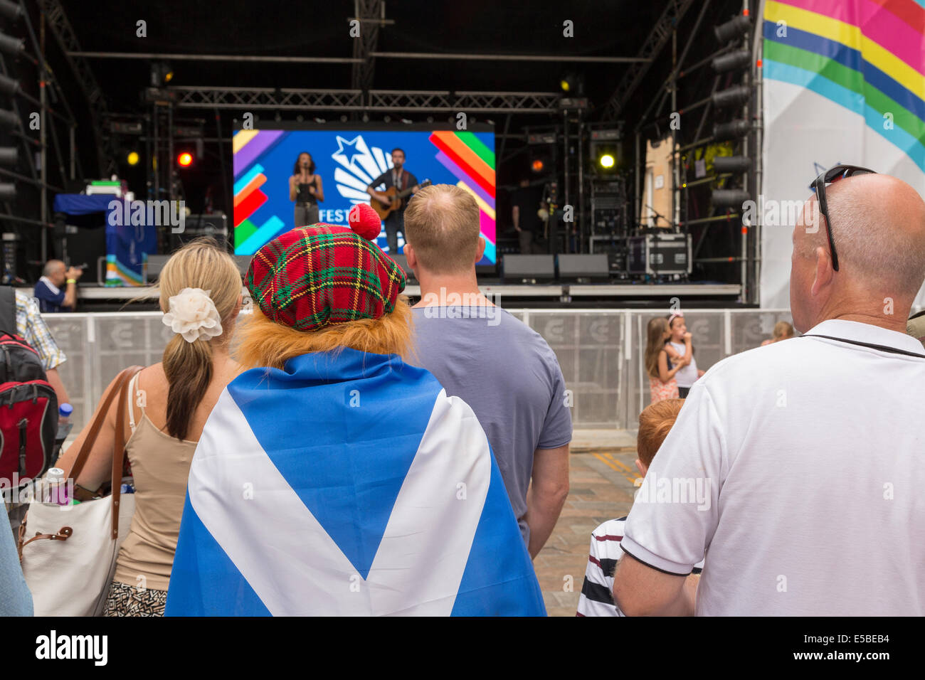 Boy with Scottish flag draped over his shoulders watches a performance ...