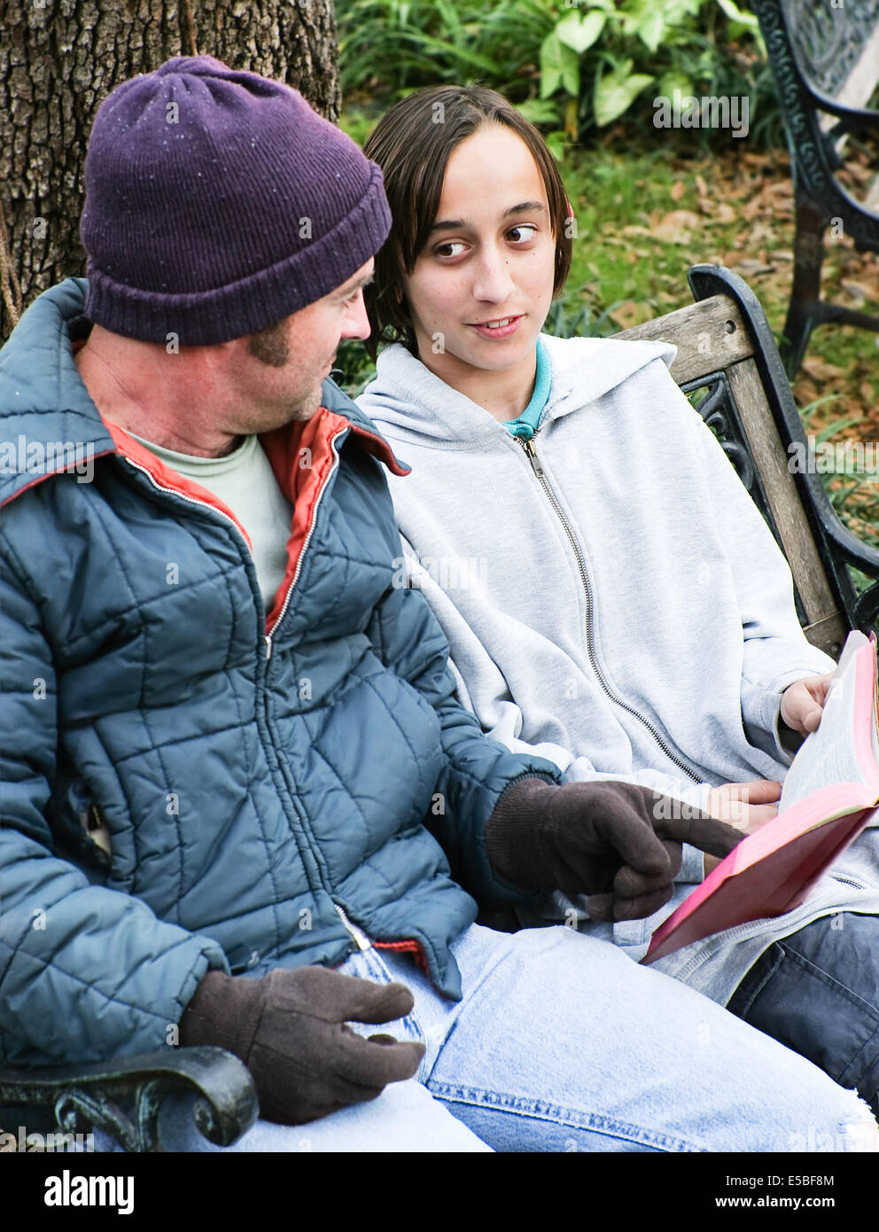 Homeless father and son reading the Bible, or a teen volunteer ...