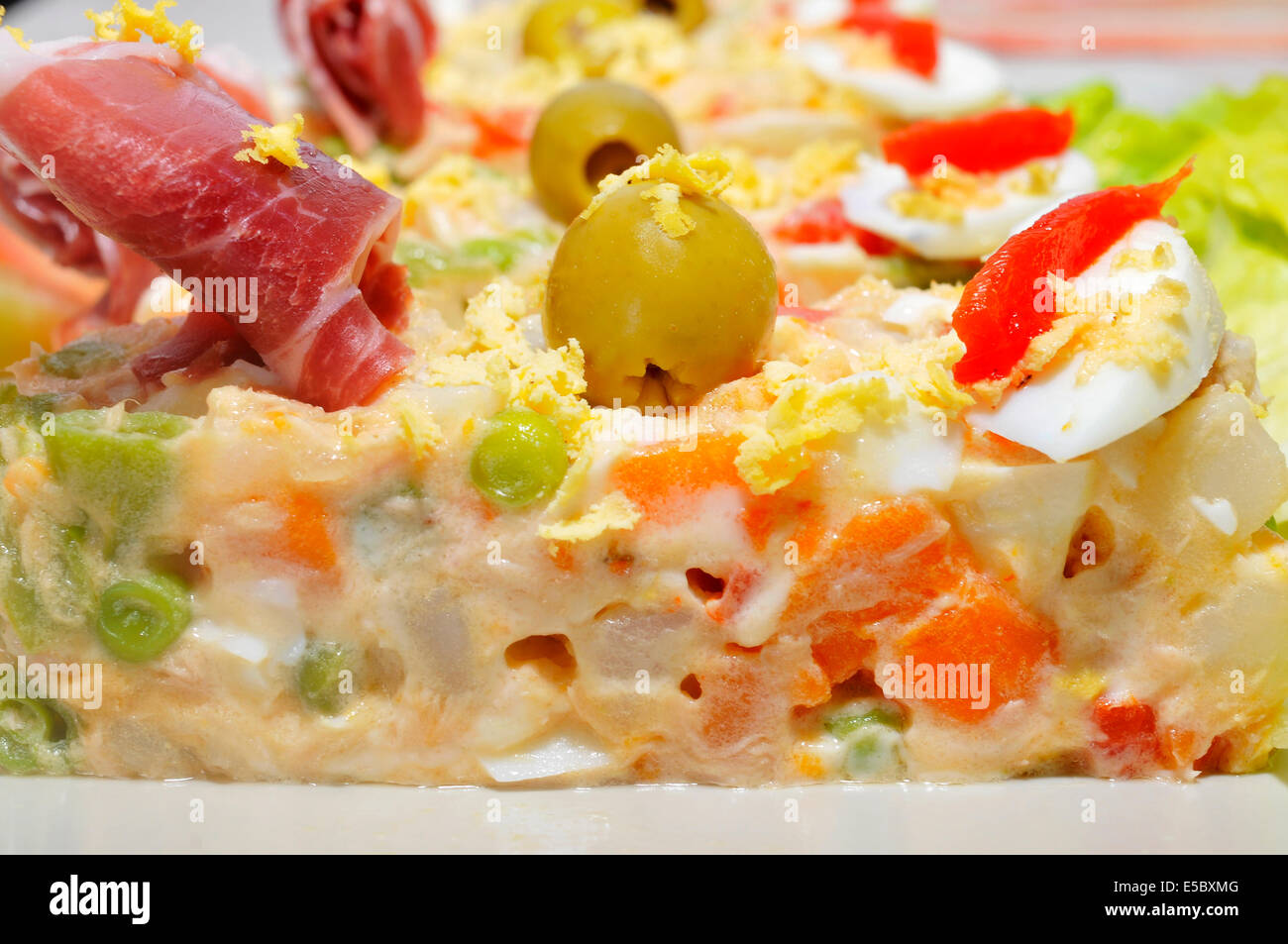 closeup of a plate with spanish ensaladilla rusa, russian salad, topped ...